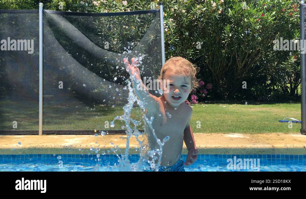 Toddler baby boy at swimming pool splashing water to camera Stock Video ...