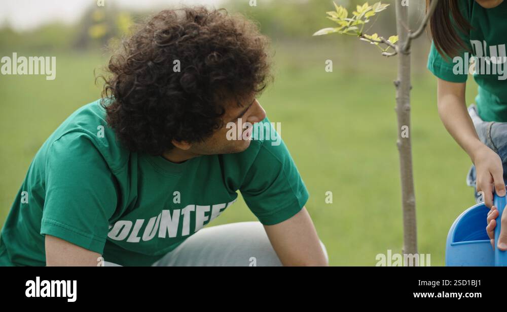Three volunteers of different age planting tree in park. Young ...