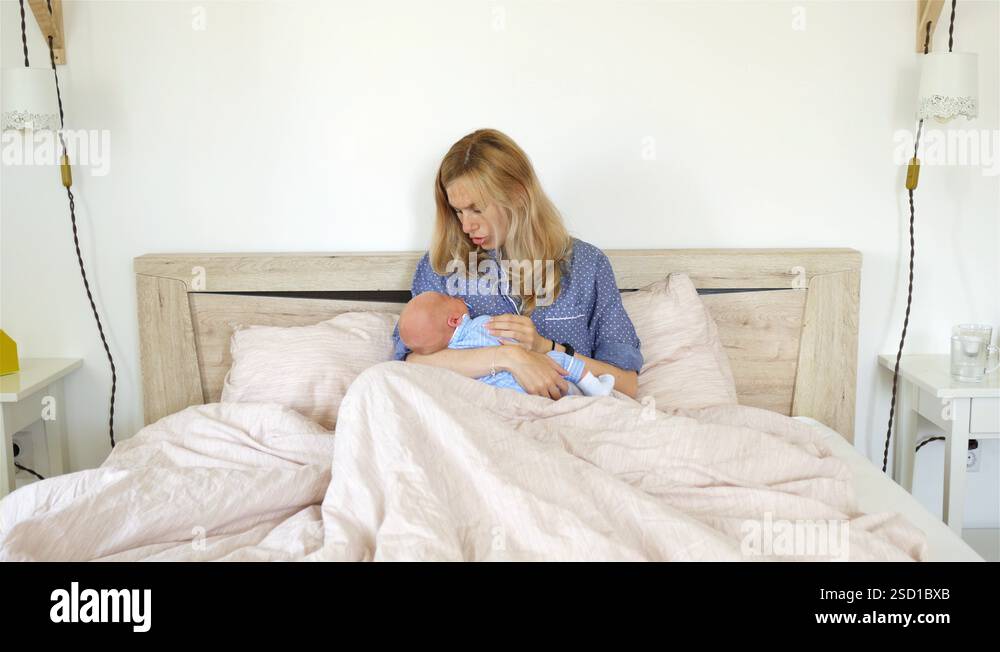 young mother soothes a crying baby lying on the bed Stock Video Footage ...