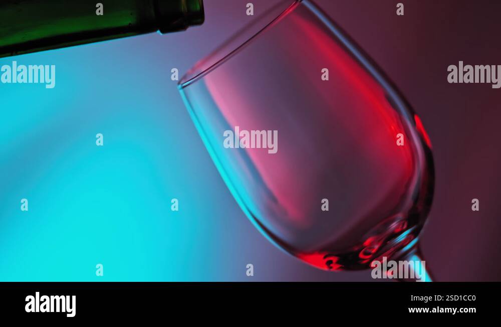 Red wine forms beautiful wave. Wine pouring in glass at red and blue ...