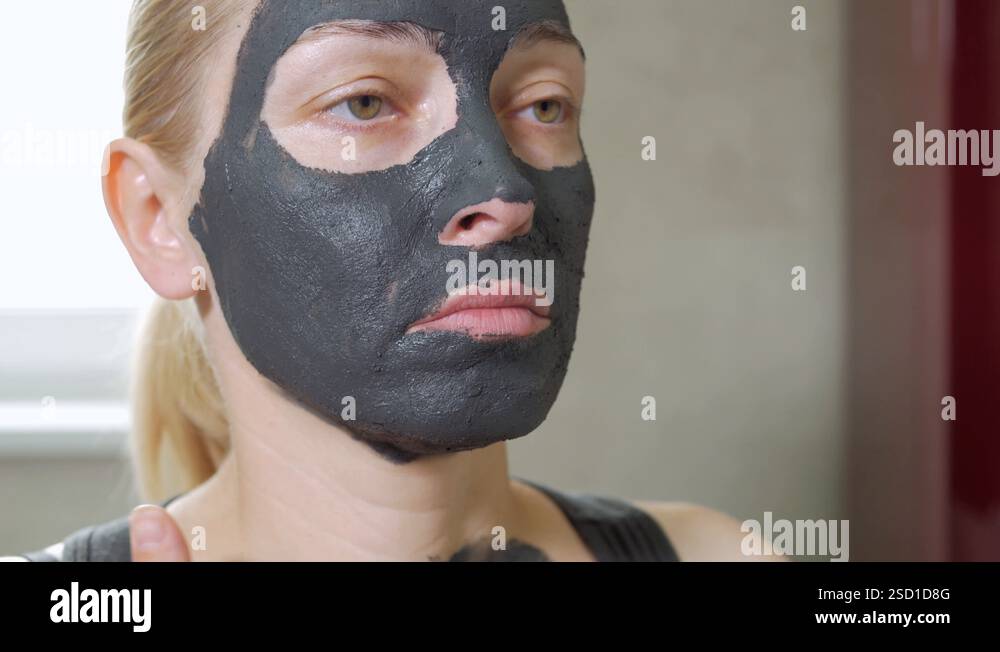 The woman puts a mud mask on a face. Face care. Mud Spa procedures. Day ...