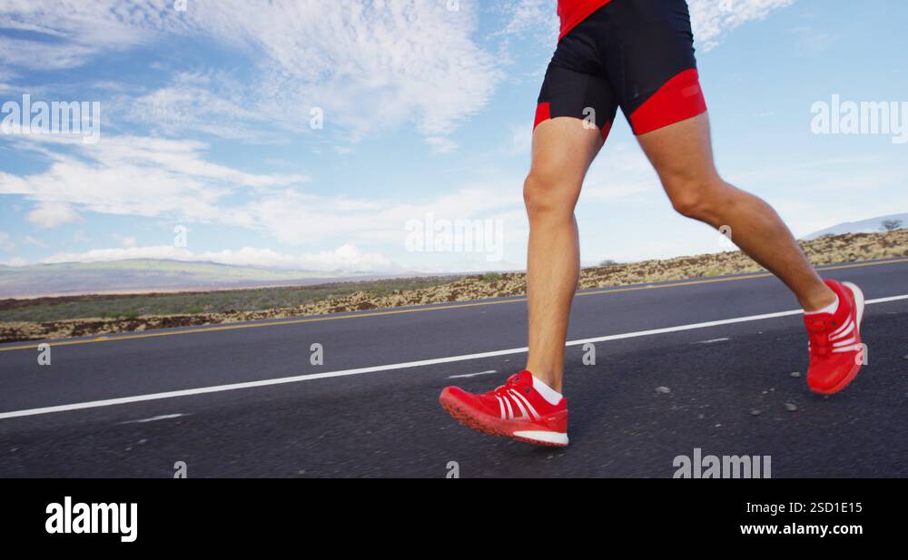 Close up athlete legs running on road fit man runner jogging sprinting ...