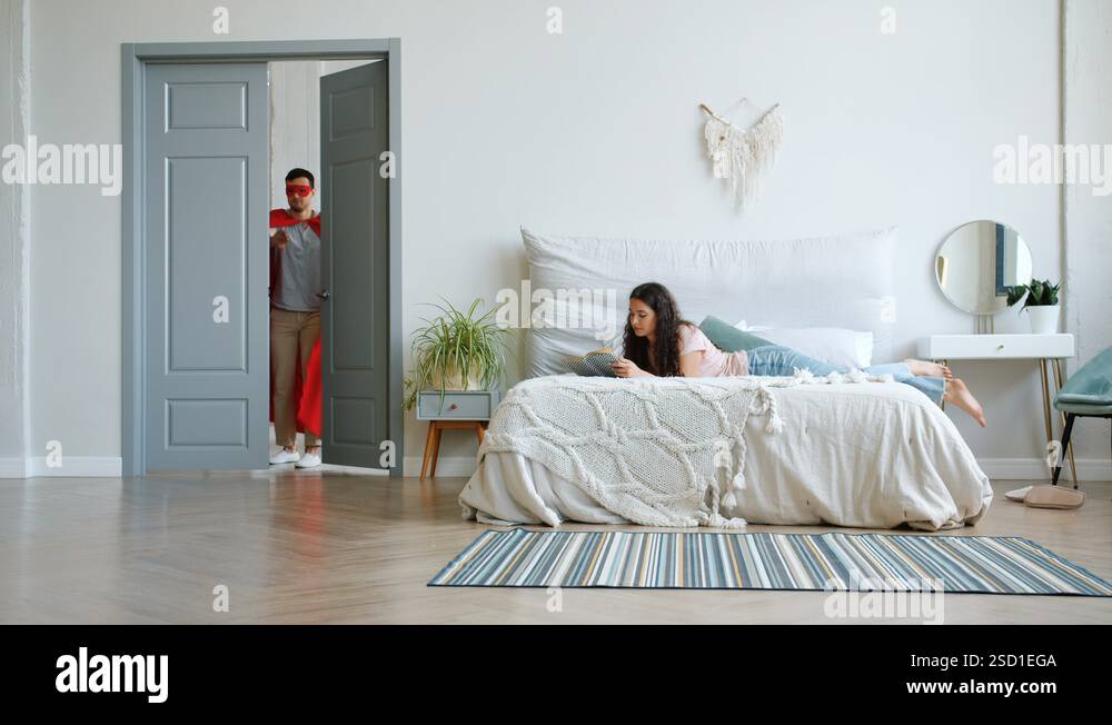 Guy in superhero costume running into room where girl reading book in ...
