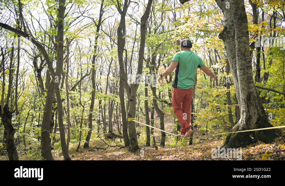 A Slack man aged with a beard in sportswear walks balancing on the ...