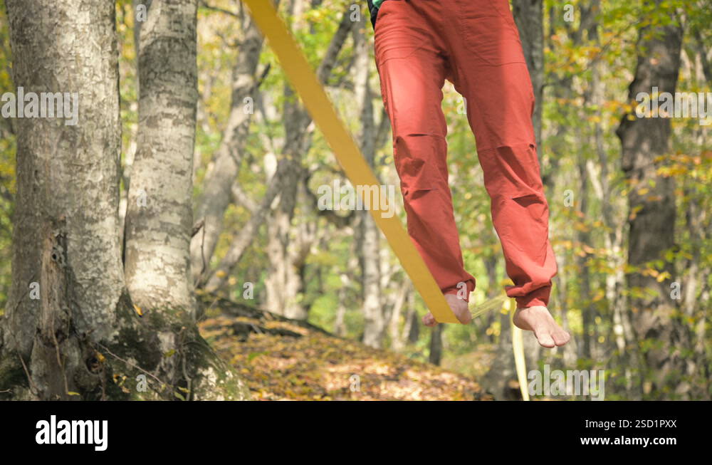 A Slack man aged with a beard in sportswear walks balancing on the ...