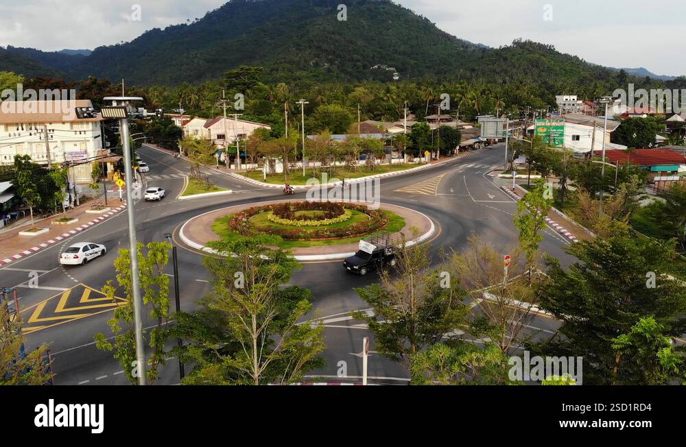 Cars riding on roundabout in small town near jungle. Vehicles riding on ...