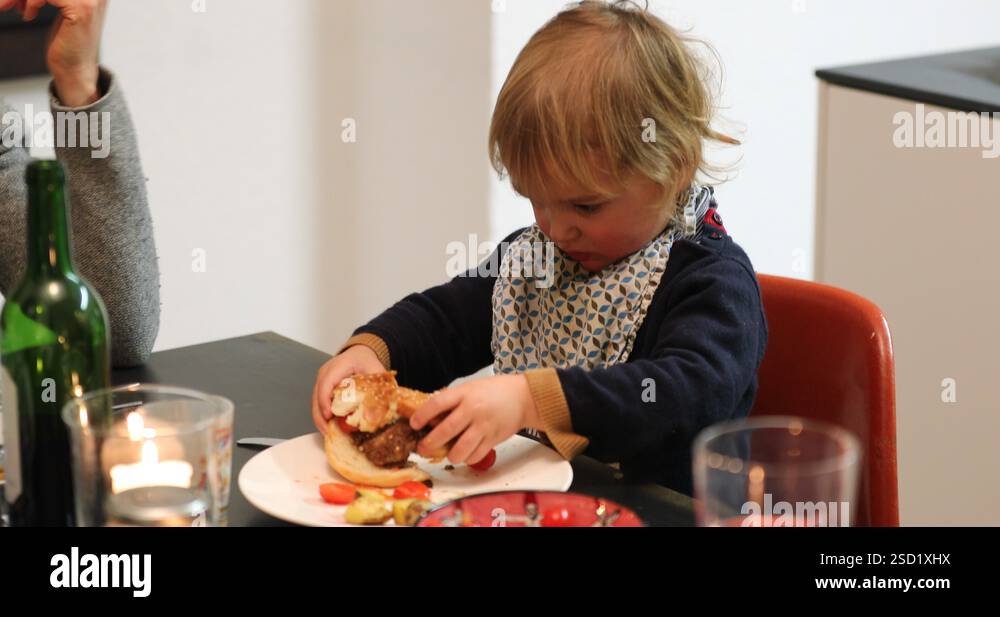 Baby toddler eating burger for dinner. Young boy eating hamburger for ...