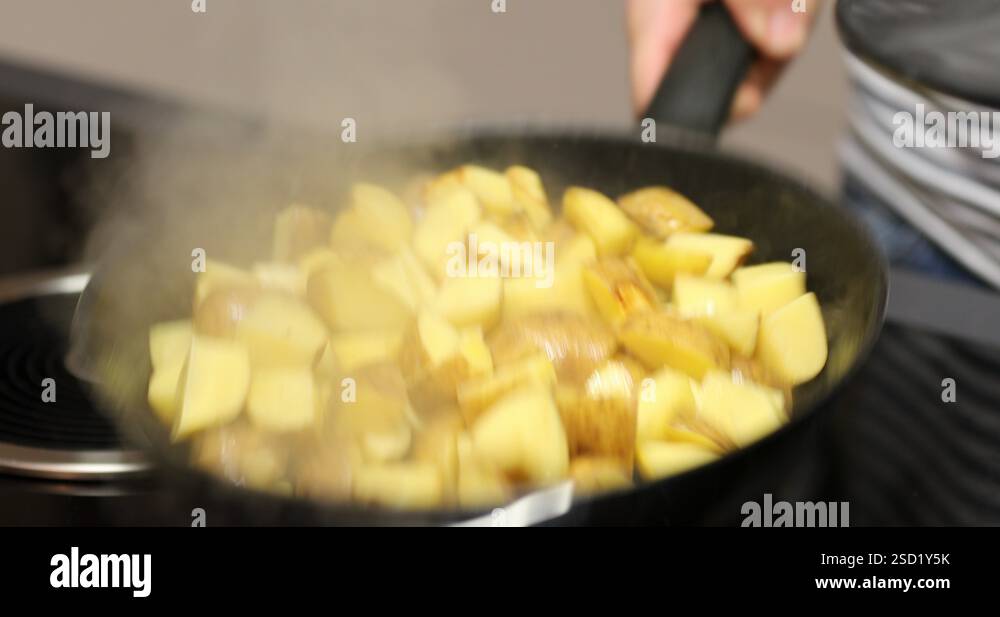 Man preparing sauteed potatoes throwing potatoes up in the air with ...