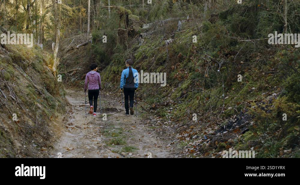 Caucasian couple or friends practicing nordic walking on a scenic ...
