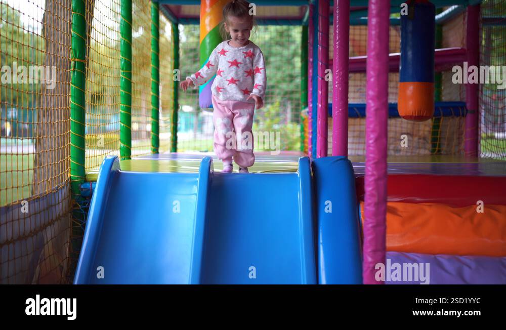 Little Girl Kid goes down from the plastic Slides to the Balls on a ...