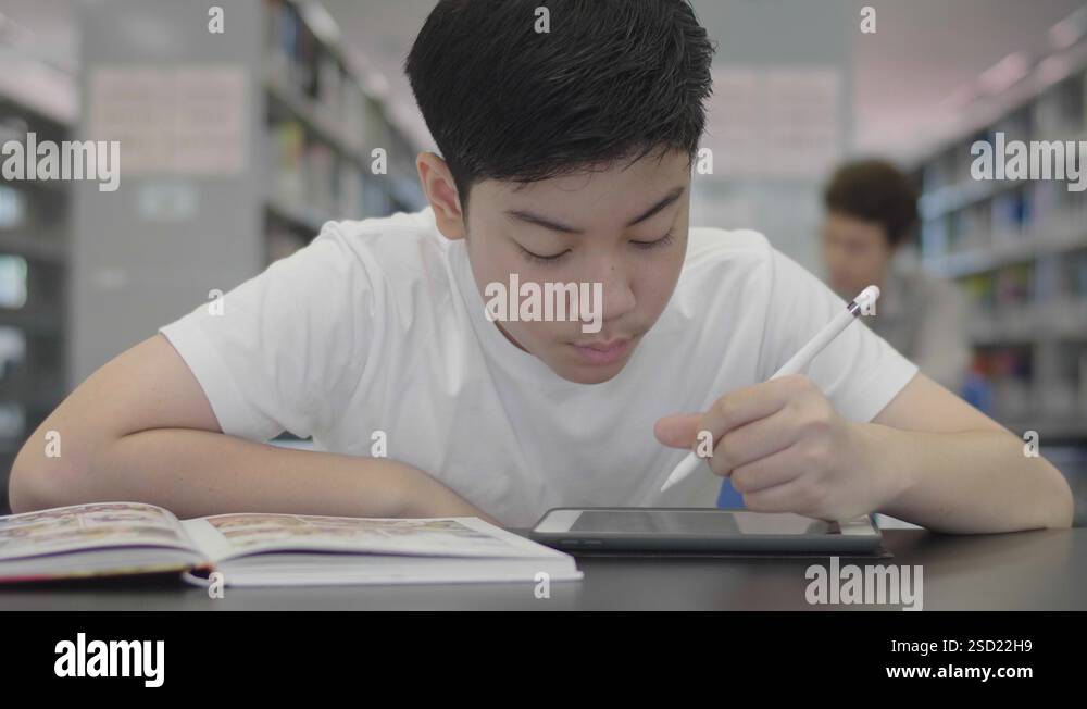 Asian preteens boys using tablet computer at library Stock Video ...