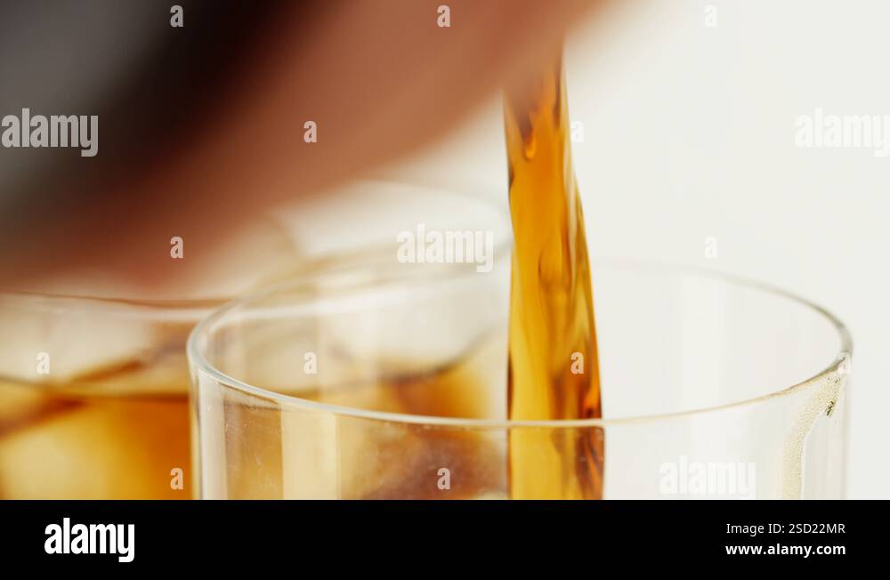 Pouring sparkling cola soft drink into a glass, close-up slow motion ...