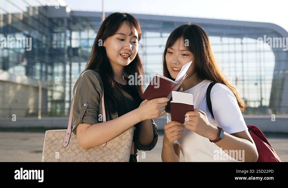 Pretty elated young asian women looking at their air tickets on the ...