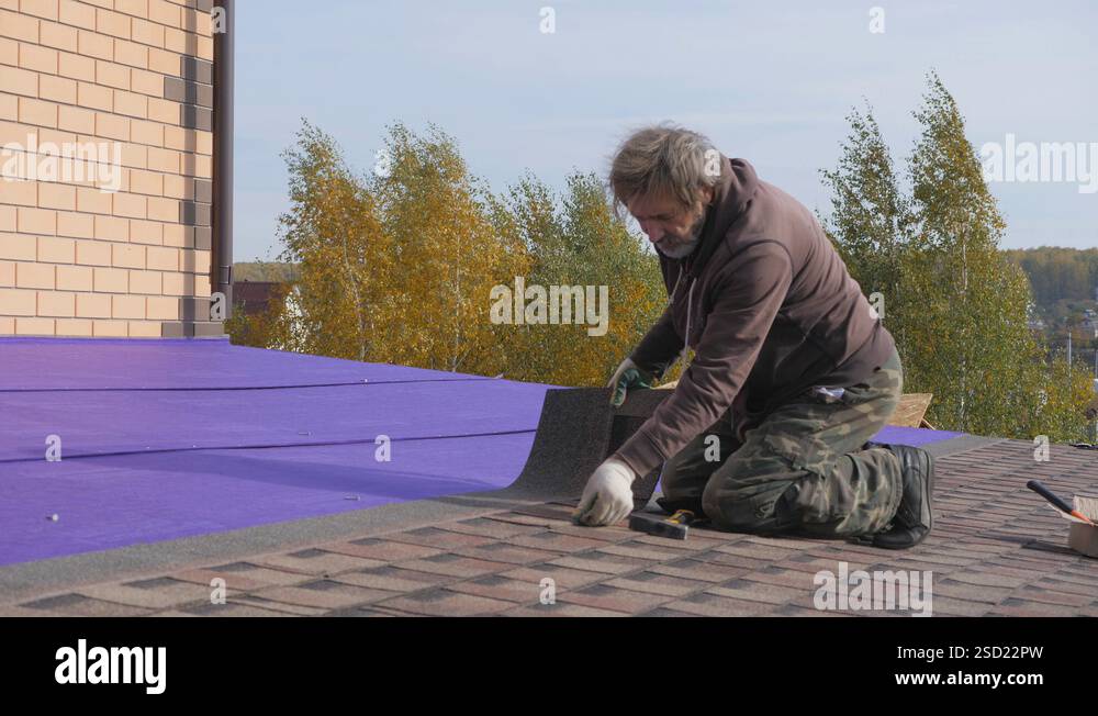 Laying a soft roof. Work at height. Laying a sheet of roofing material ...