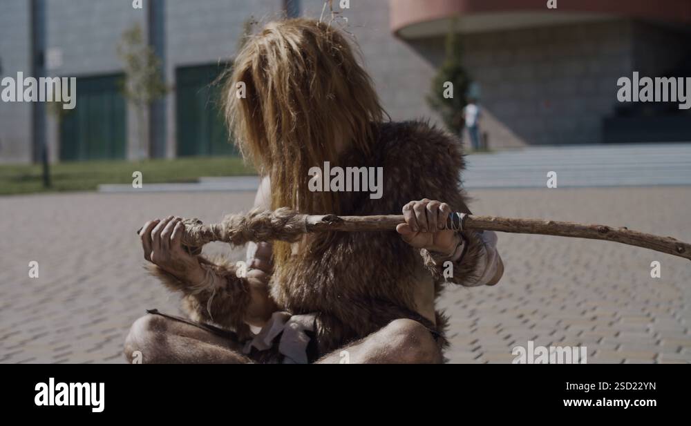 Neanderthal of hunter-gatherers in animal fur holding repairs weapon ...