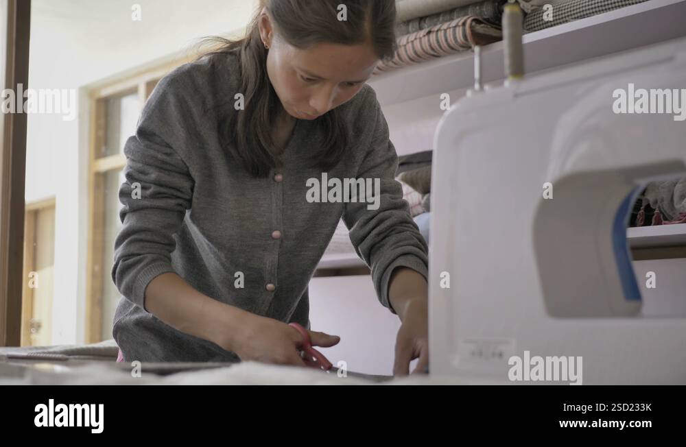 An Asian/Indian female tailor hand cutting clothes with a scissor Stock ...