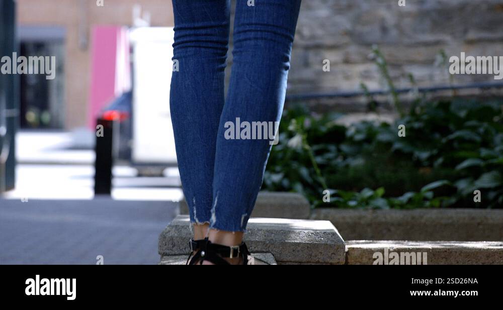 Young woman walking on planter ledge next to side walk - from behind ...