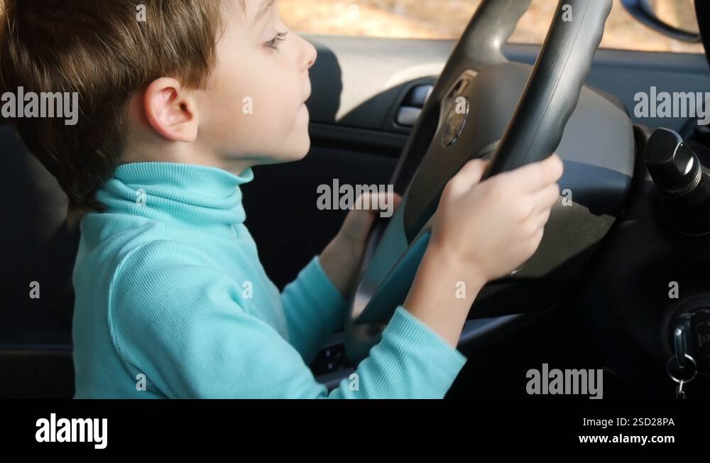 A little boy turns the wheel of a car sitting in a car seat Stock Video ...