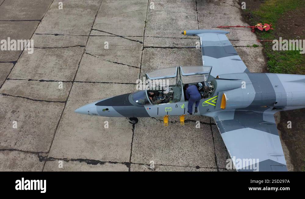 The pilot sits in cockpit of gray jet plane on ground. Top view of ...