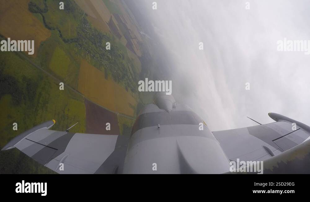 Gray fighter plane make barrel roll maneuver against a cloudy sky. Axis ...