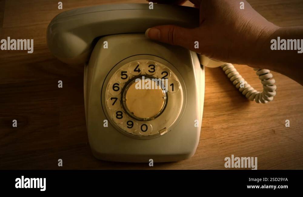 woman hand picking a receiver and dialing on a rotary dial telephone ...