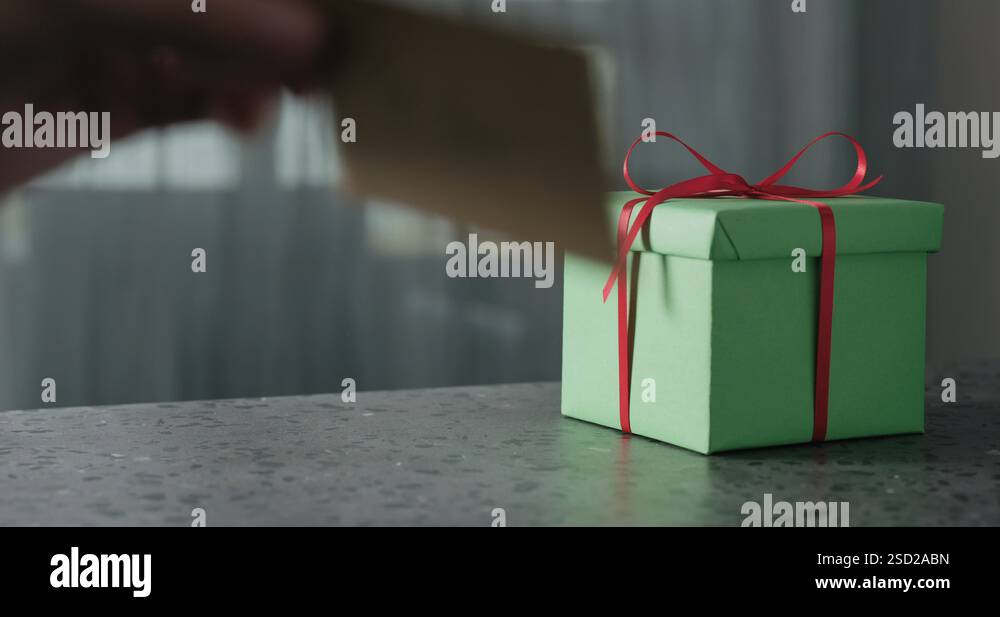Slow motion man hand put for you paper card next to green gift box on ...