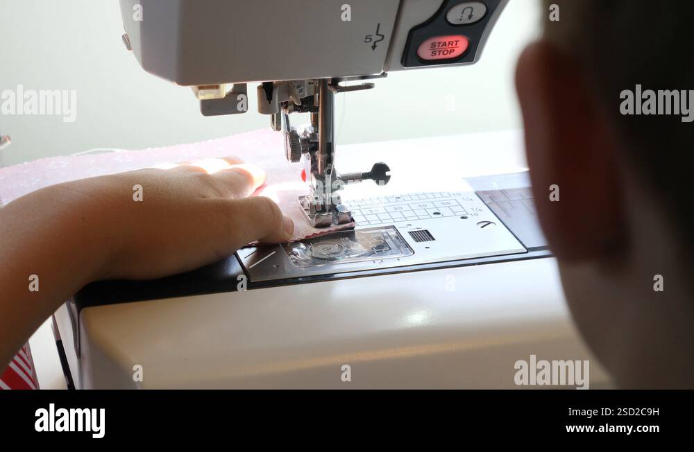 A cute little boy learns how to use a sewing machine at home Stock ...