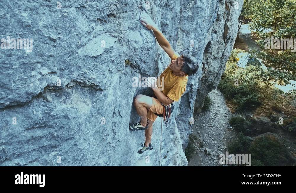 man rock climber starting to climb on a cliff, searching, reaching and ...