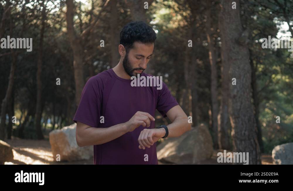 Smiling man using a smartwatch to monitor his progress. Male athlete ...