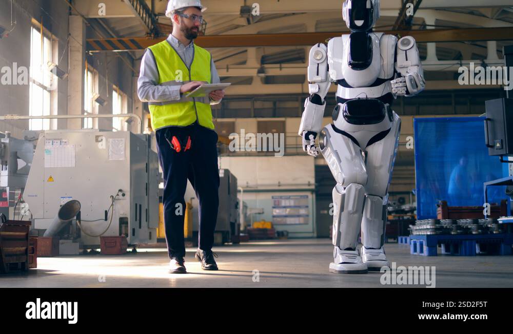 Man watches a robot walk in a factory room Stock Video Footage - Alamy