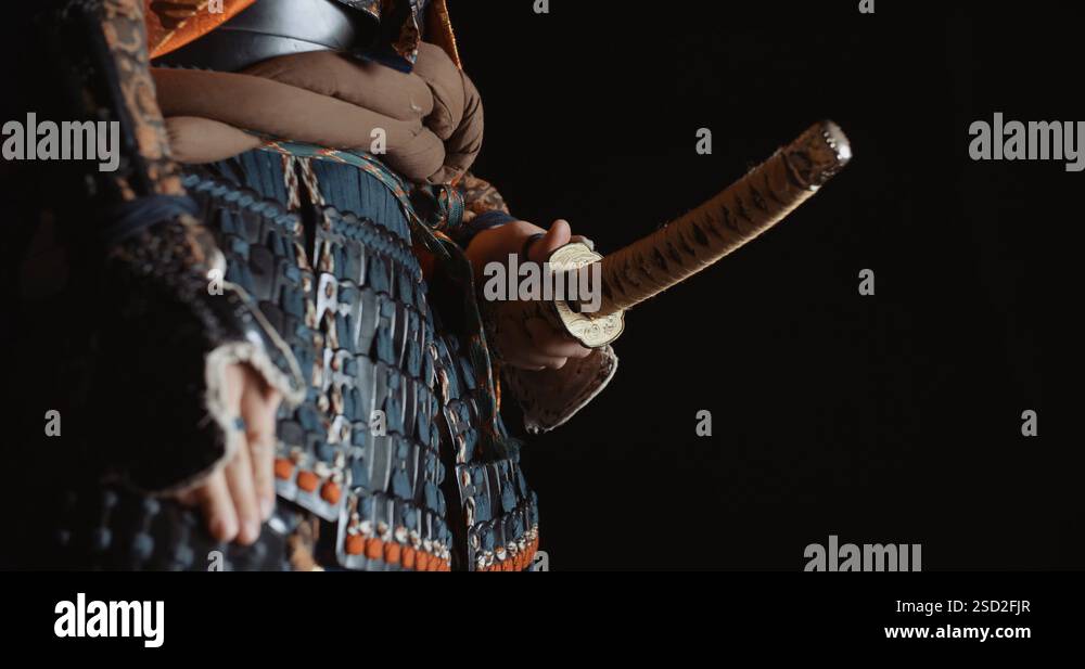 A man in japanese samurai armour is taking a sword out of his ...