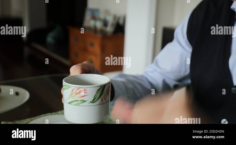Older man sipping cup of coffee at home for breakfast, cleaning mouth ...
