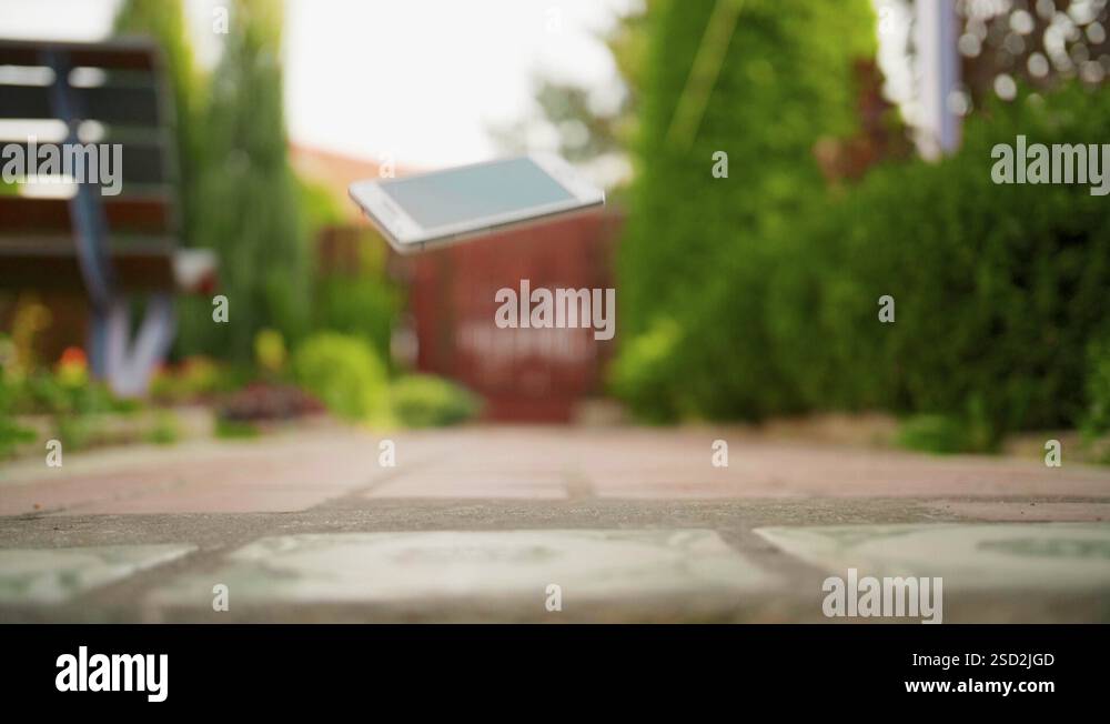 Mobile phone falls and breaks on the concrete ground in slow motion ...