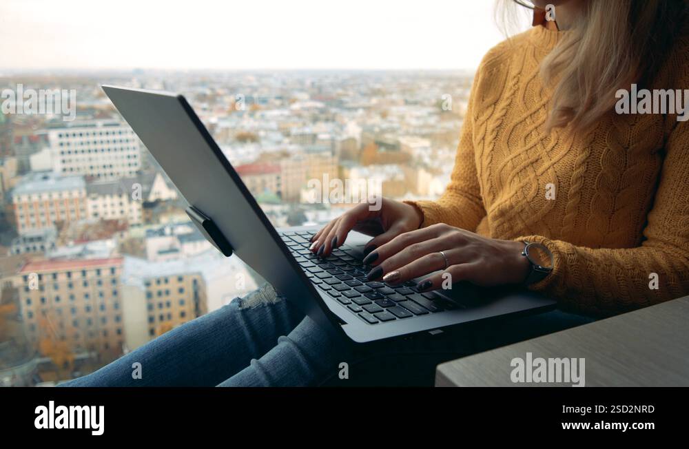 A freelancer lady with a laptop at the window with a city view Stock ...