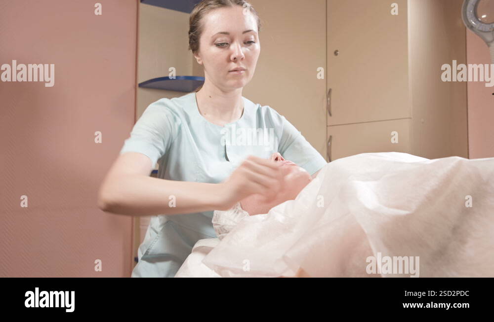 Girl beautician in a mask and gloves makes a salubrious facial massage to an Stock Video Footage ...