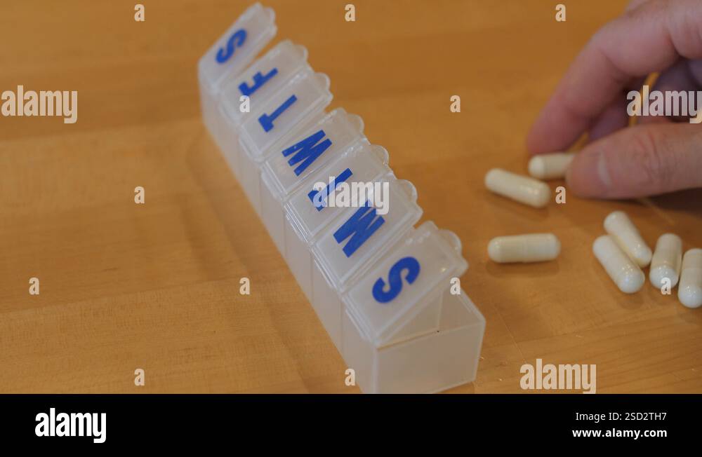Adding supplement capsules to weekly pill box organizer Stock Video ...