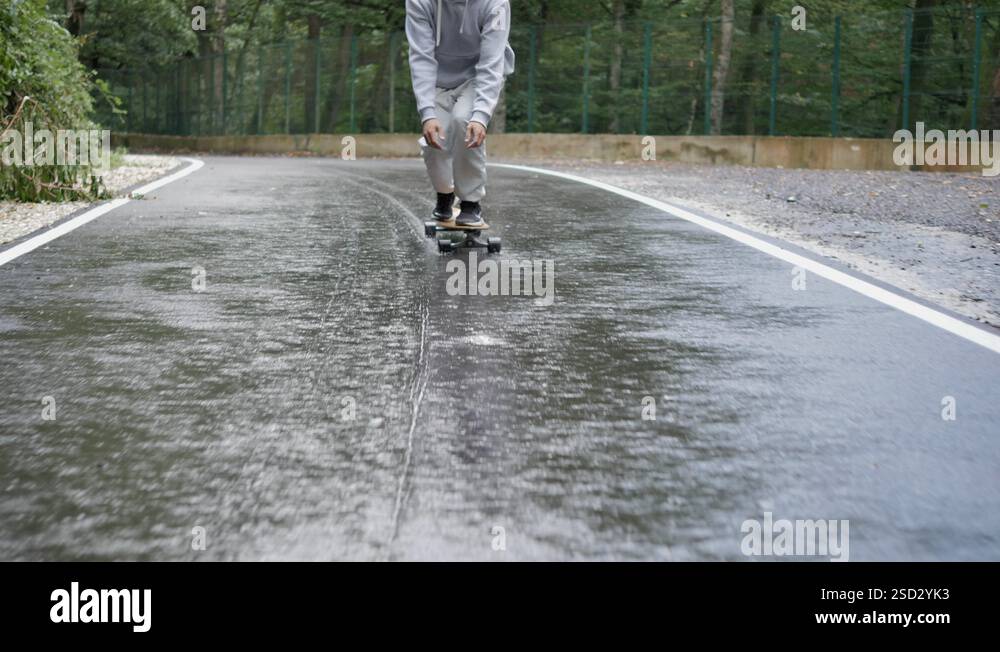 Skateboarder legs riding on longboard on winding road through mountain ...