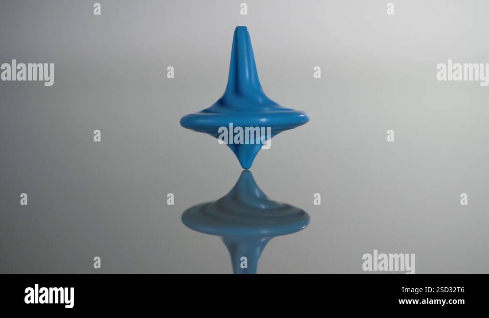 Blue spinning top spinning. Whirligig in action is reflected on mirror ...