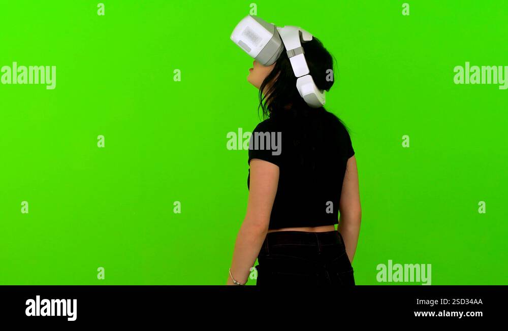 Amazed teenage girl using a VR application or game, over green screen ...