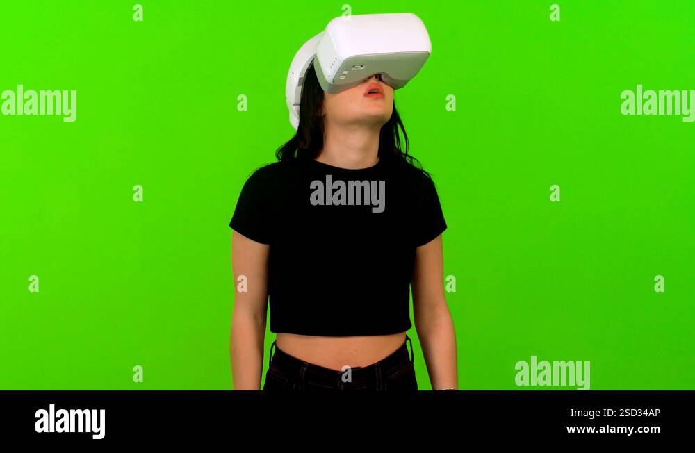 Amazed teenage girl using a VR application or game, over green screen ...