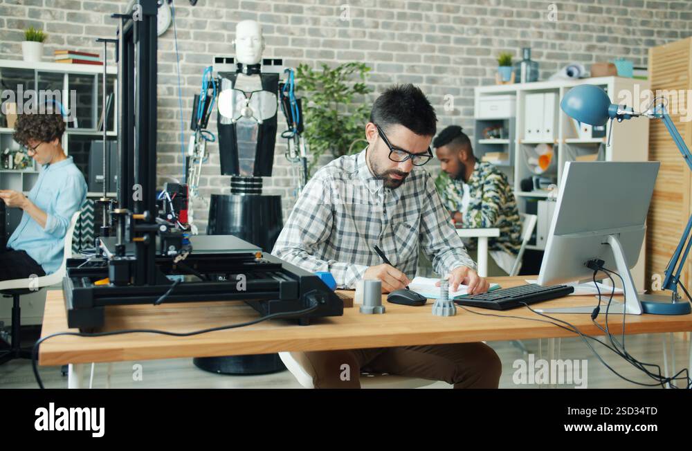 Group of people designing robot in office using 3d printer and computer ...