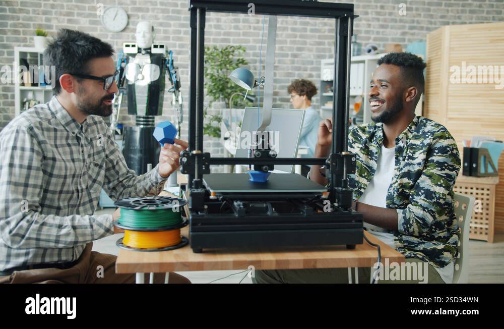 Young people talking watching 3d printer modeling plastic detail for ...