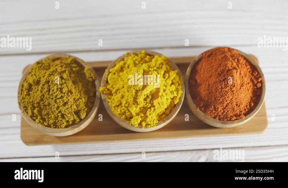 Three various spices in wooden bowls on white desk - turmeric, curry ...