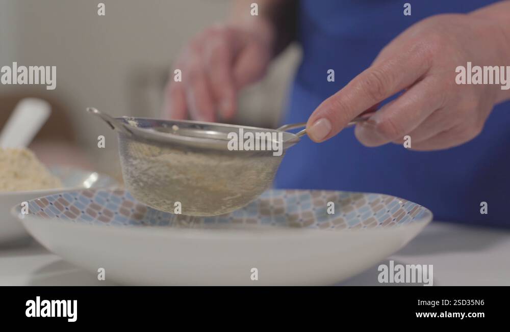 Close-up of mature female Caucasian hands sifting flour. Senior female ...