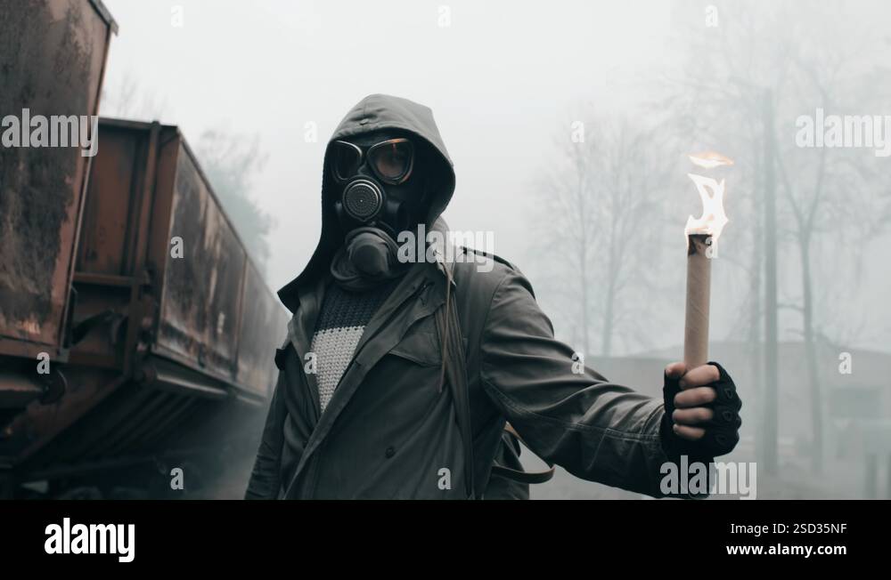 Stalker in gas mask walks near carriages at train station with fire in ...