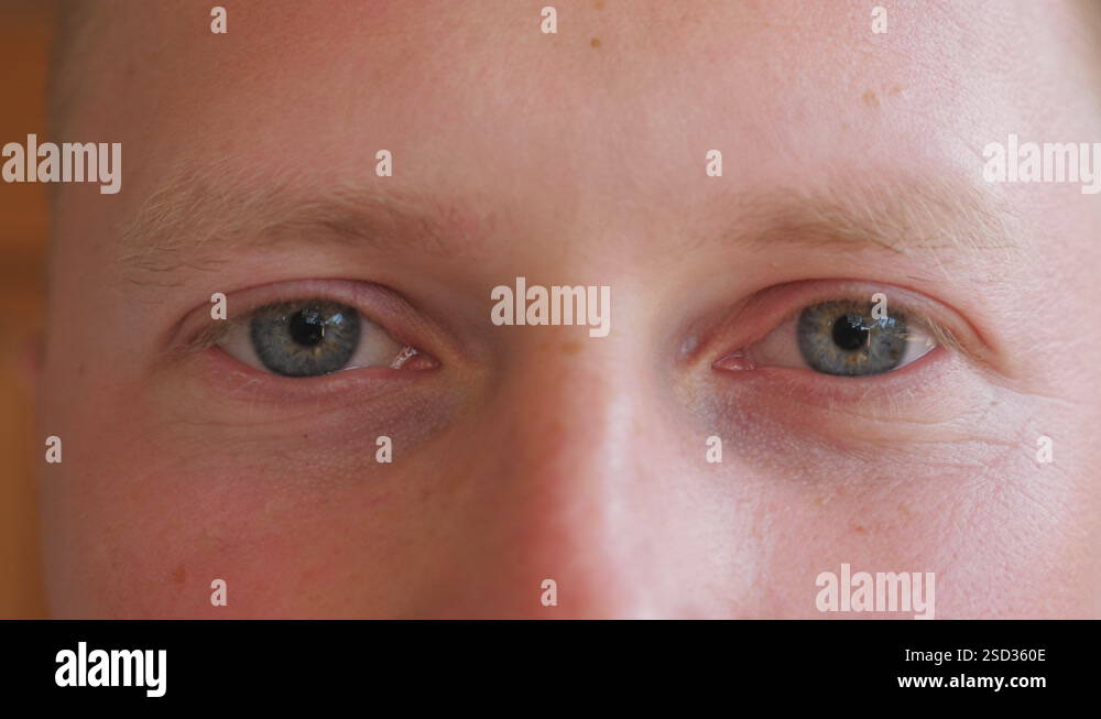 Close up blue eyes of guy staring and blinking with a tired sight ...