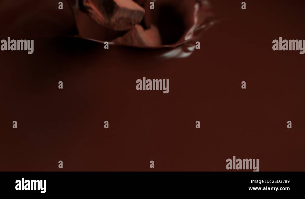 Super Slow Motion Shot of Raw Chocolate Chunks Falling into Melted ...