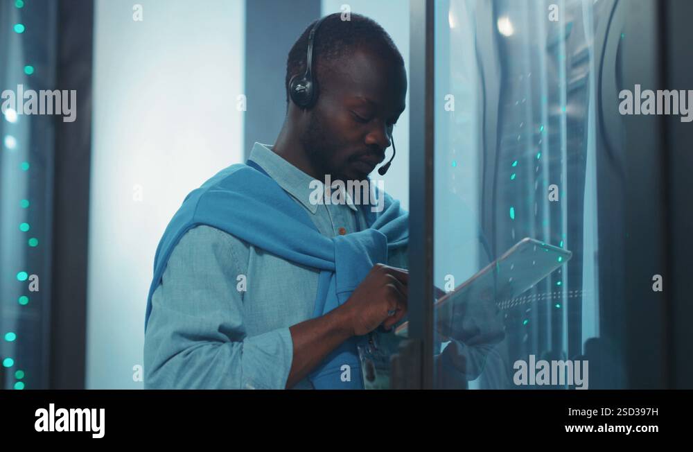 Black african IT technician with tablet examining open rack cabinet ...
