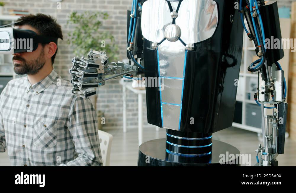Human and robotic arm doing same movements, guy in vr glasses testing ...