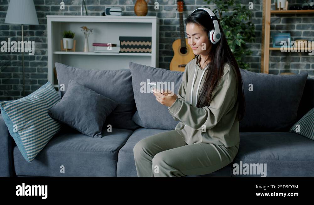 Young woman listening to music in headphones and using smartphone at ...